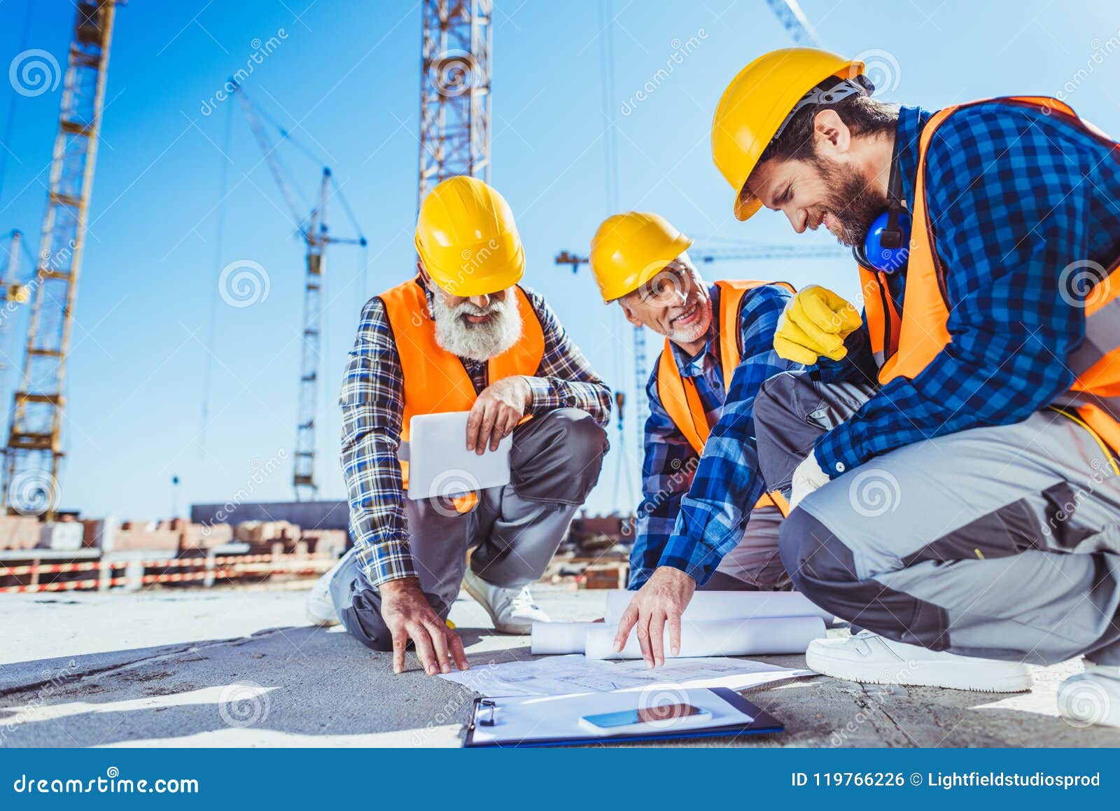 Three Construction Workers Sitting on Concrete at Construction Site ...