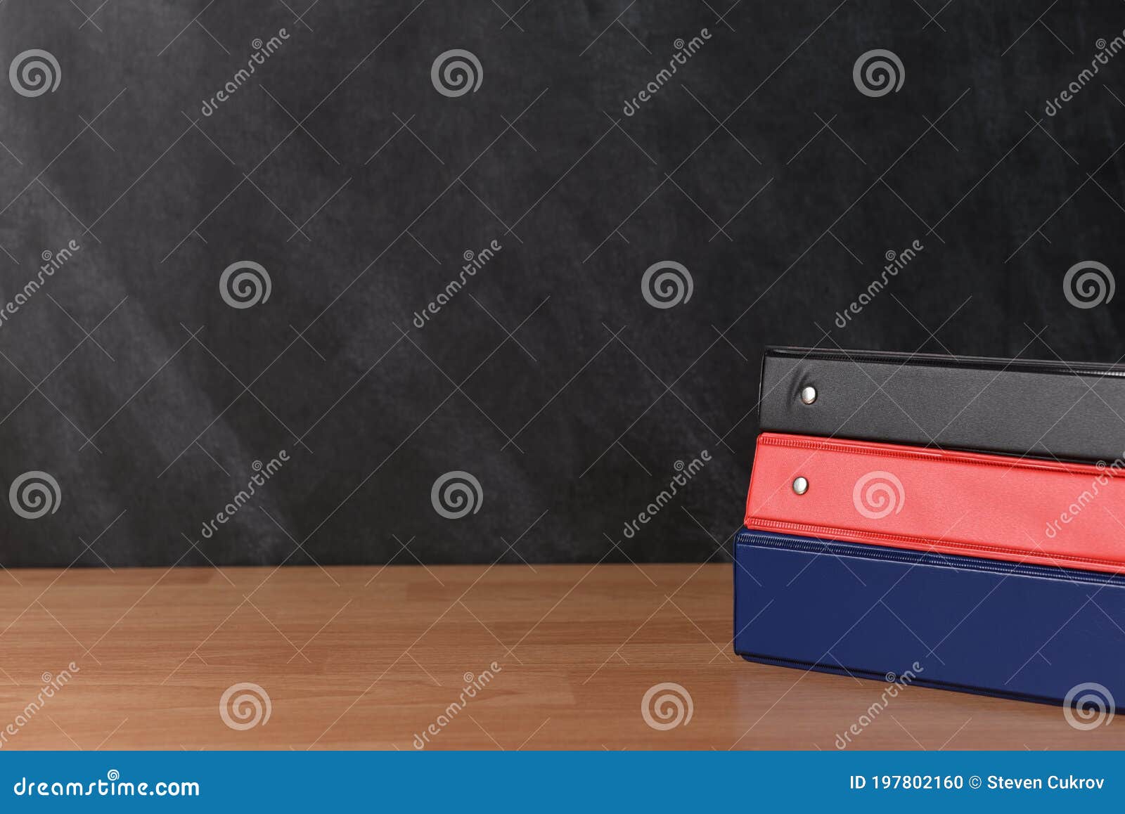 Three Different Binders Laying on a Teachers Desk in Front of a Chalk ...
