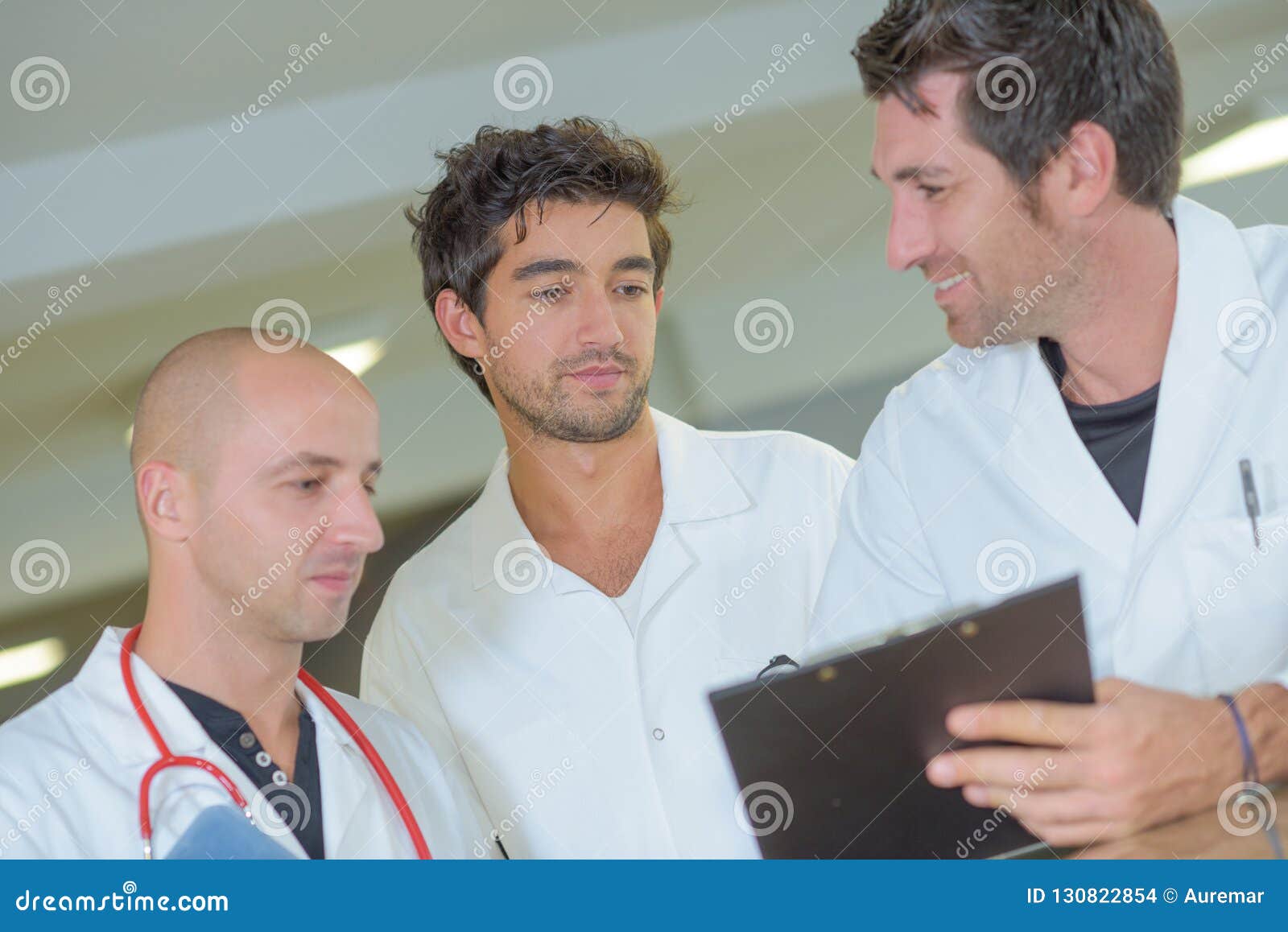 Three Doctors Looking at Clipboard Stock Photo - Image of group ...