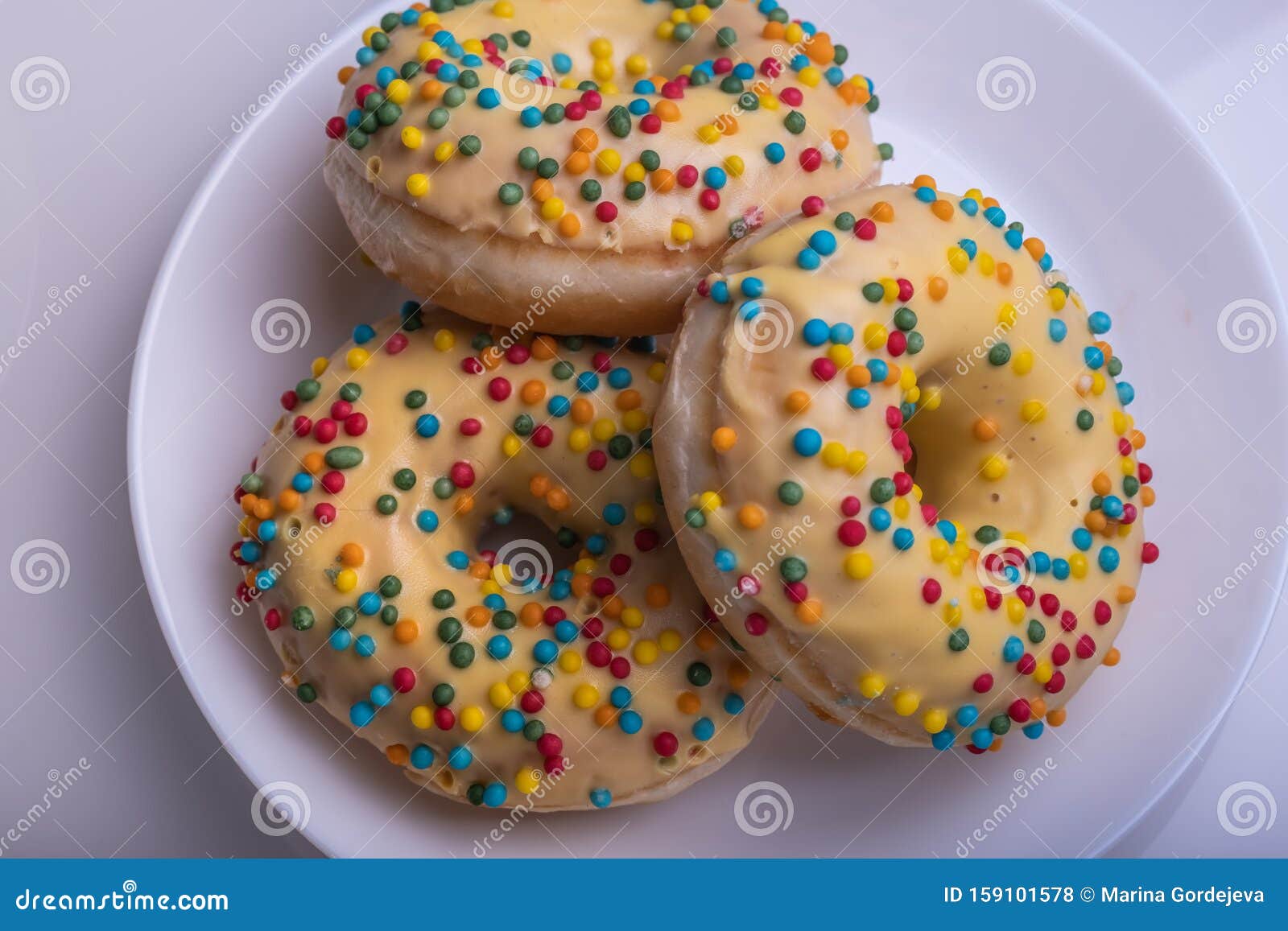 Three Donuts Coated with Yellow Icing with Sprinkles on the Table Stock ...