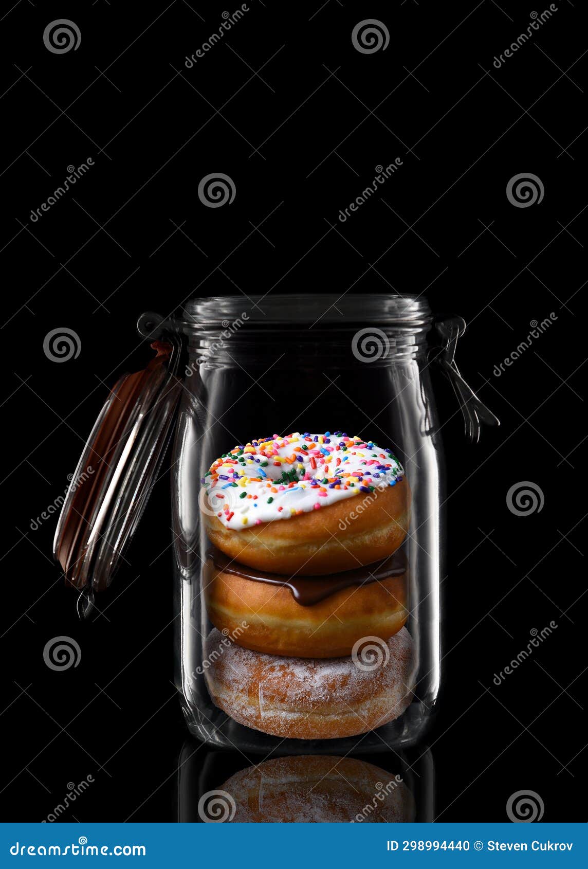 Three Donuts in a Glass Storage or Canning Jar Isolated on Black with ...