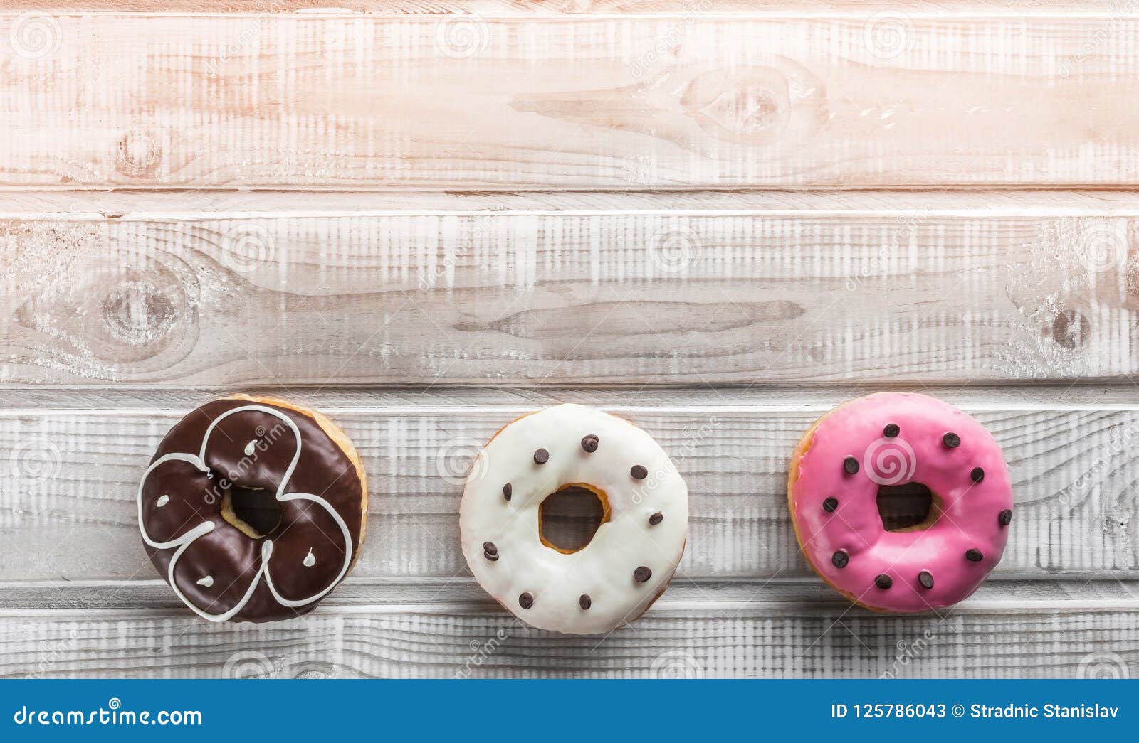 Three Donuts Placed at the Bottom of the Wooden Background. Top View ...