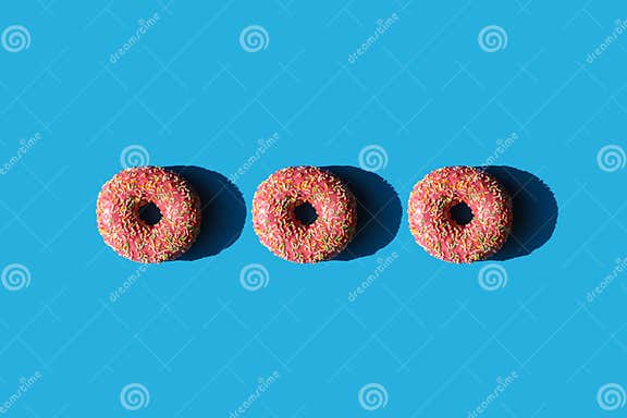 Three Donuts in a Row on a Blue Background Stock Image - Image of ...