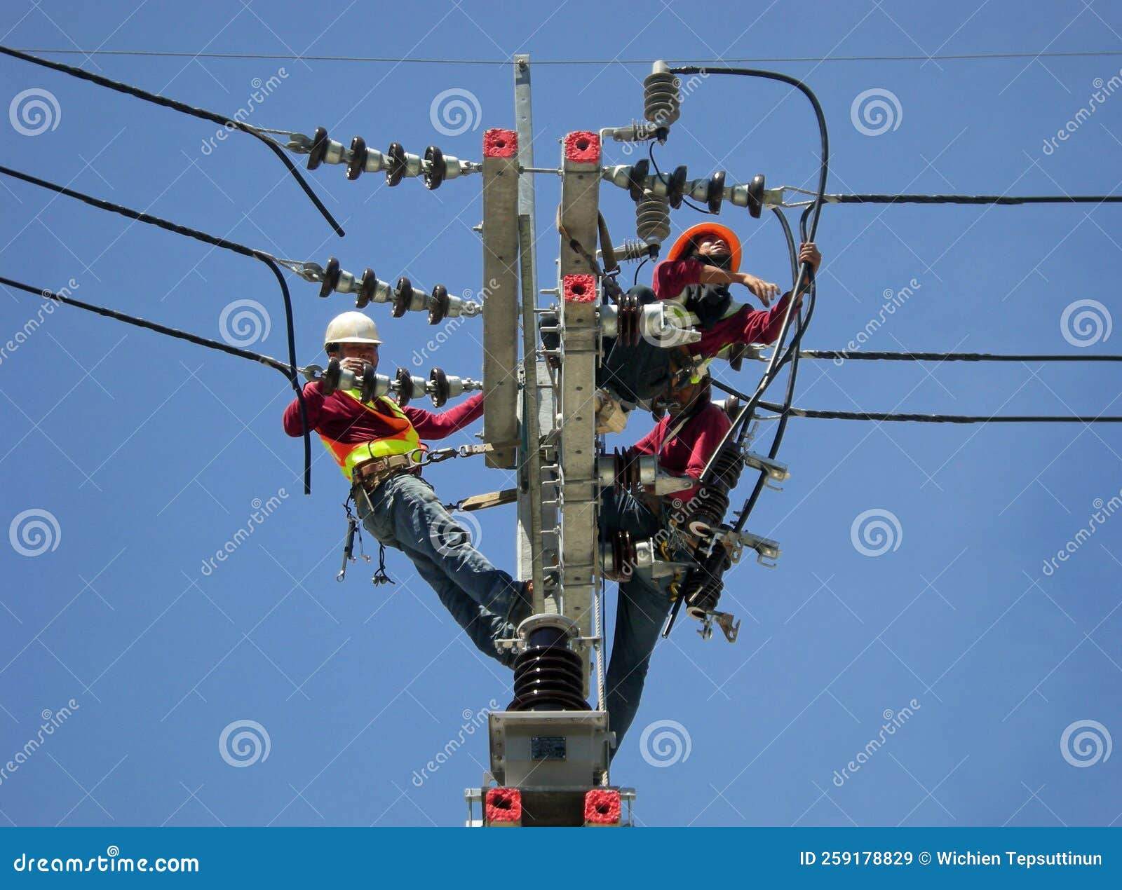 Three Electricians Installing Electrical Equipment on an Electric Pole ...