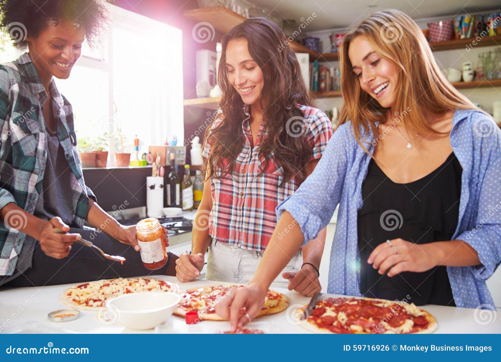 Three Female Friends Making Pizza in Kitchen Together Stock Photo ...