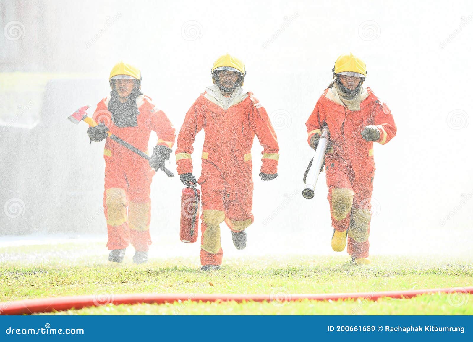 Three Firefighters in Uniform Walking Forward Holding a Fire Extinguish ...