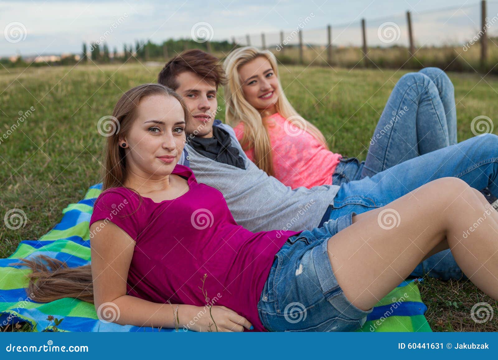 Three Friend Relaxing on Colorful Blanket in Park. Summertime. Stock ...