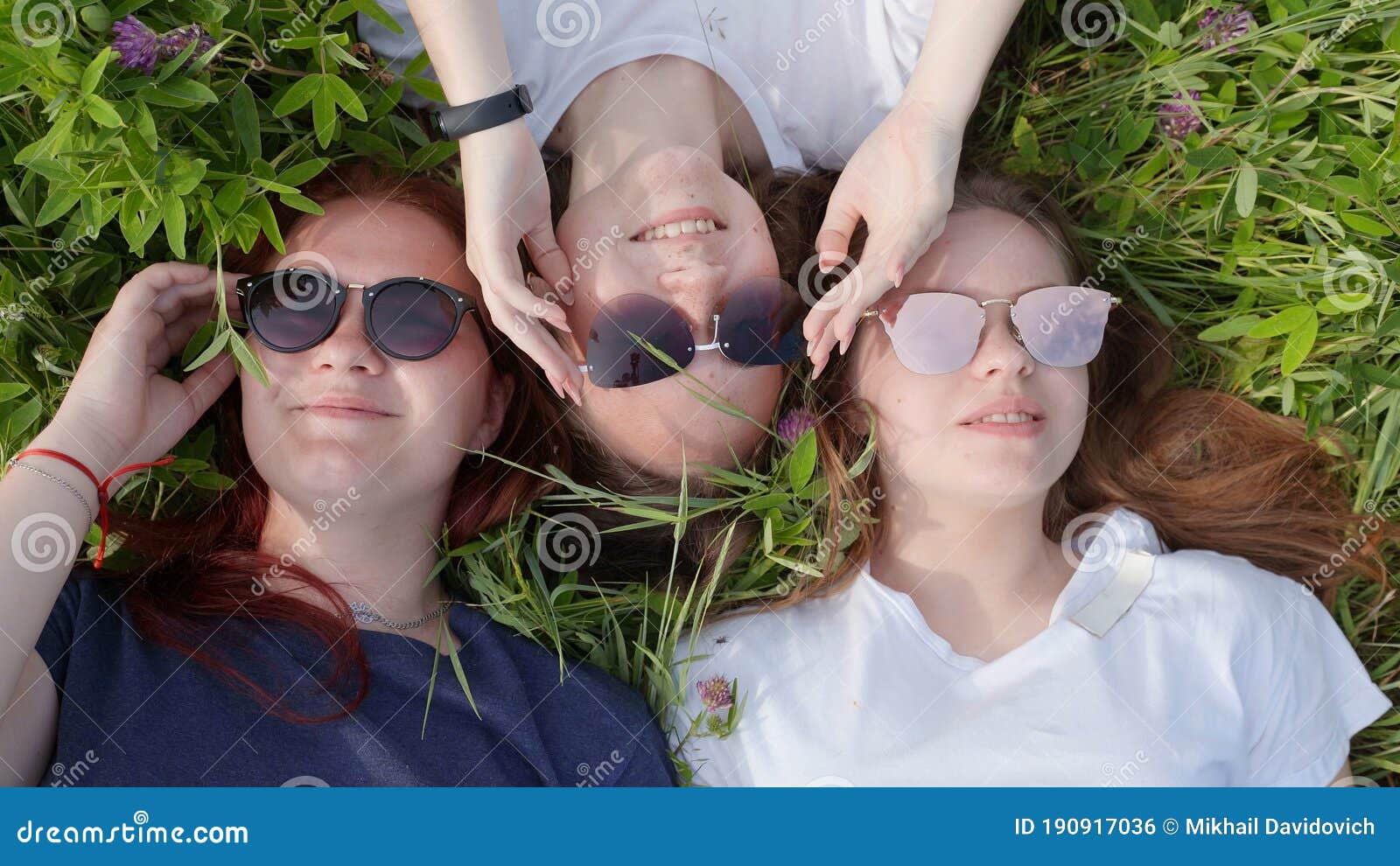 Three Friendly Girlfriends are Lying on the Grass with Sunglasses and ...