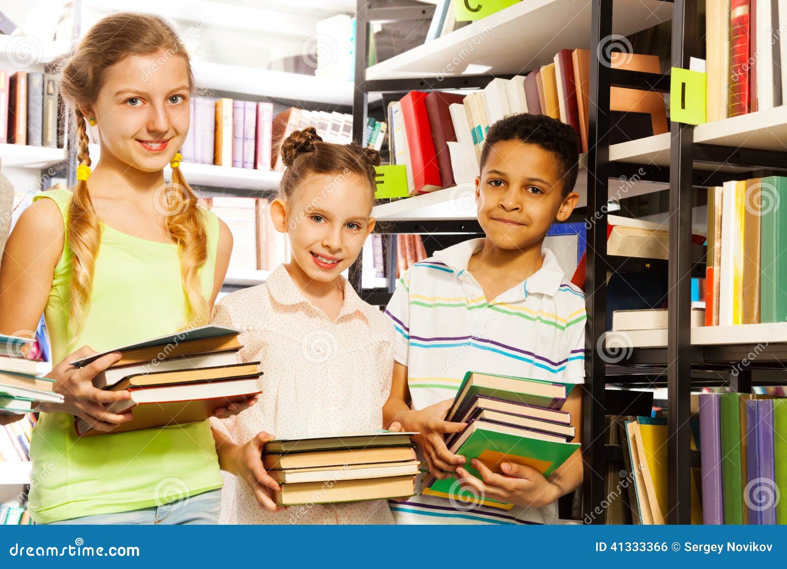 Three Friends with Books Standing Near Bookshelf Stock Photo - Image of ...