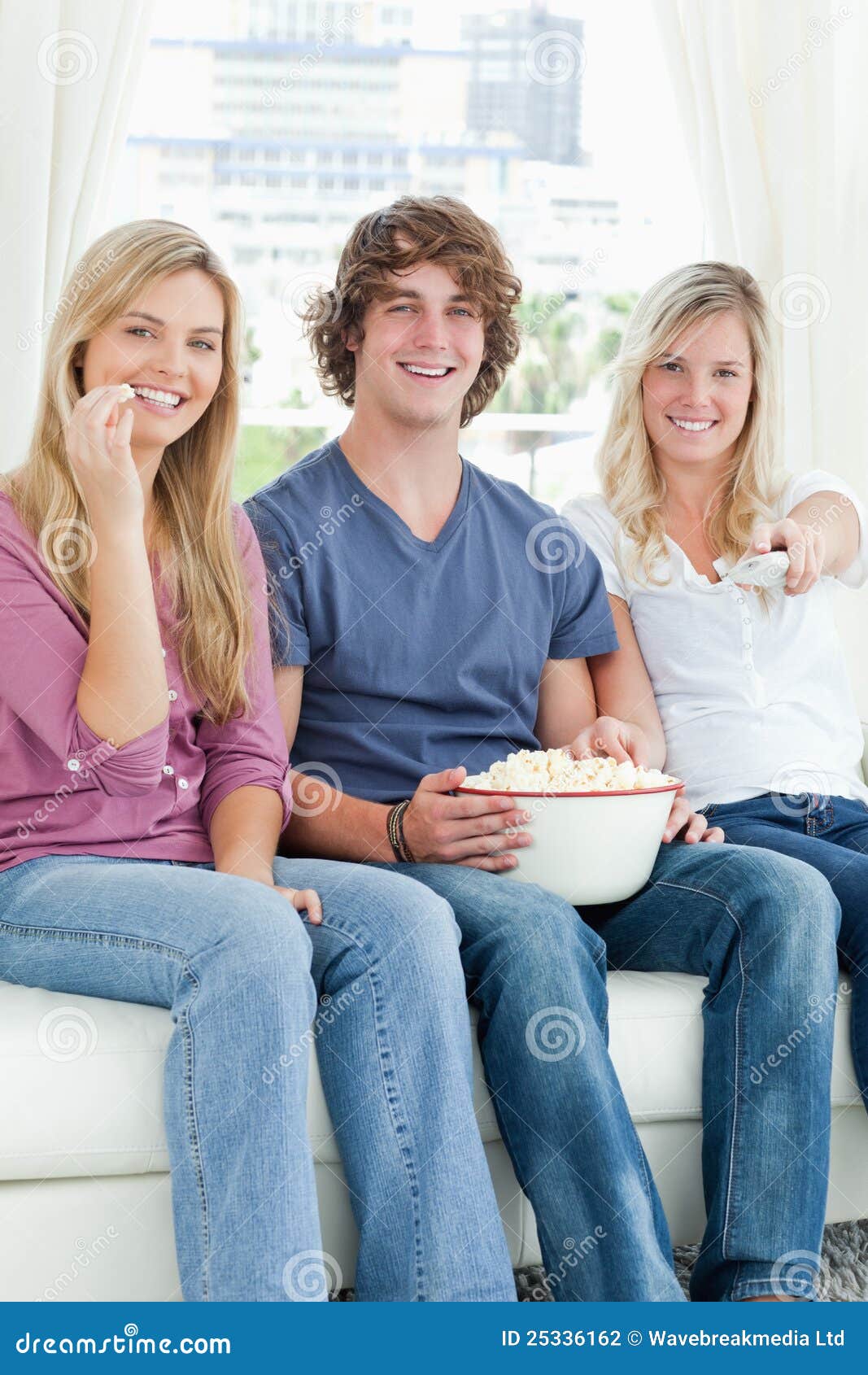 Three Friends Eating Popcorn while Smiling Stock Photo - Image of ...
