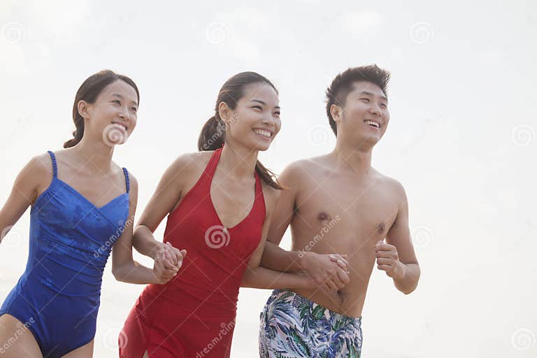 Three Friends Holding Hands and Smiling on the Beach Stock Photo ...