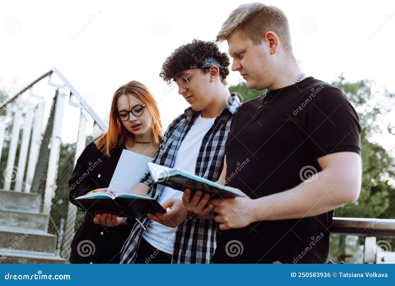 Three Friends Standing Studying with Book Outdoors. Small Group of High ...