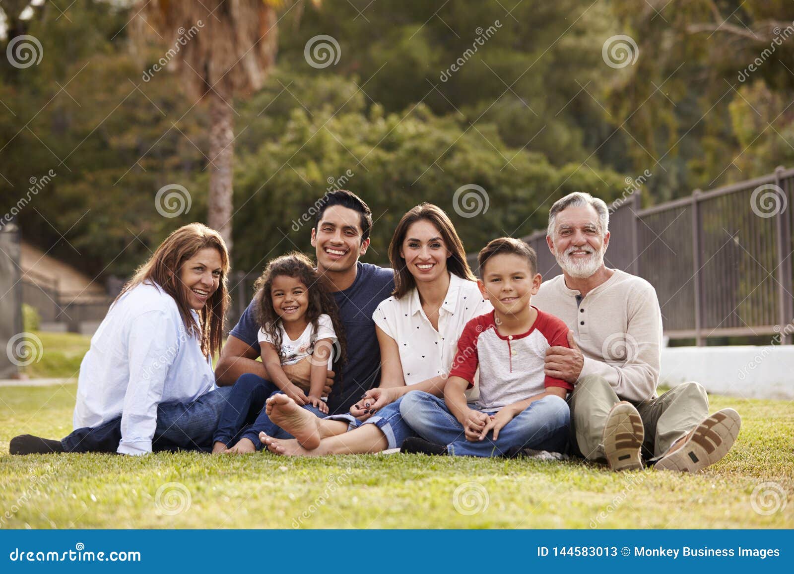 Three Generation Hispanic Family Sitting on the Grass in the Park ...