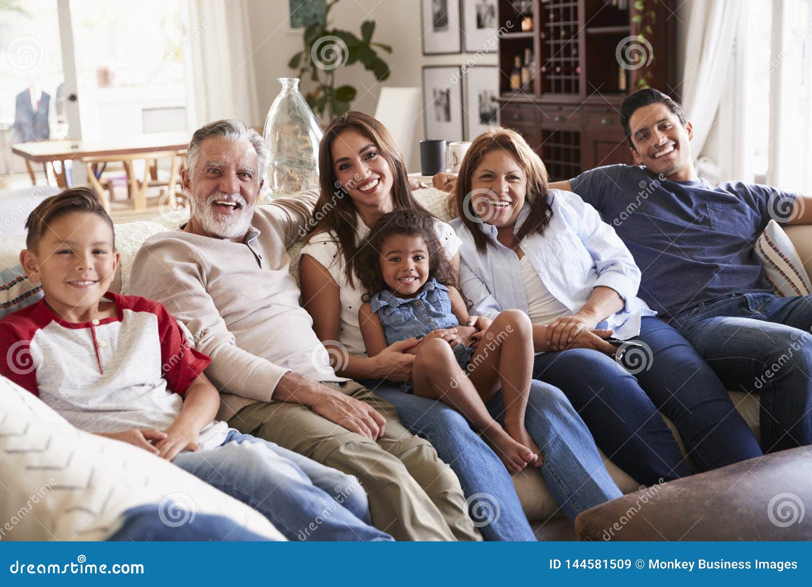 Three Generation Hispanic Family Sitting on the Sofa Watching TV ...