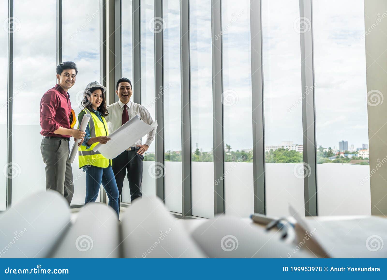 Three Happy Contractor Team Smiling at the Far End of a Desk Full of ...