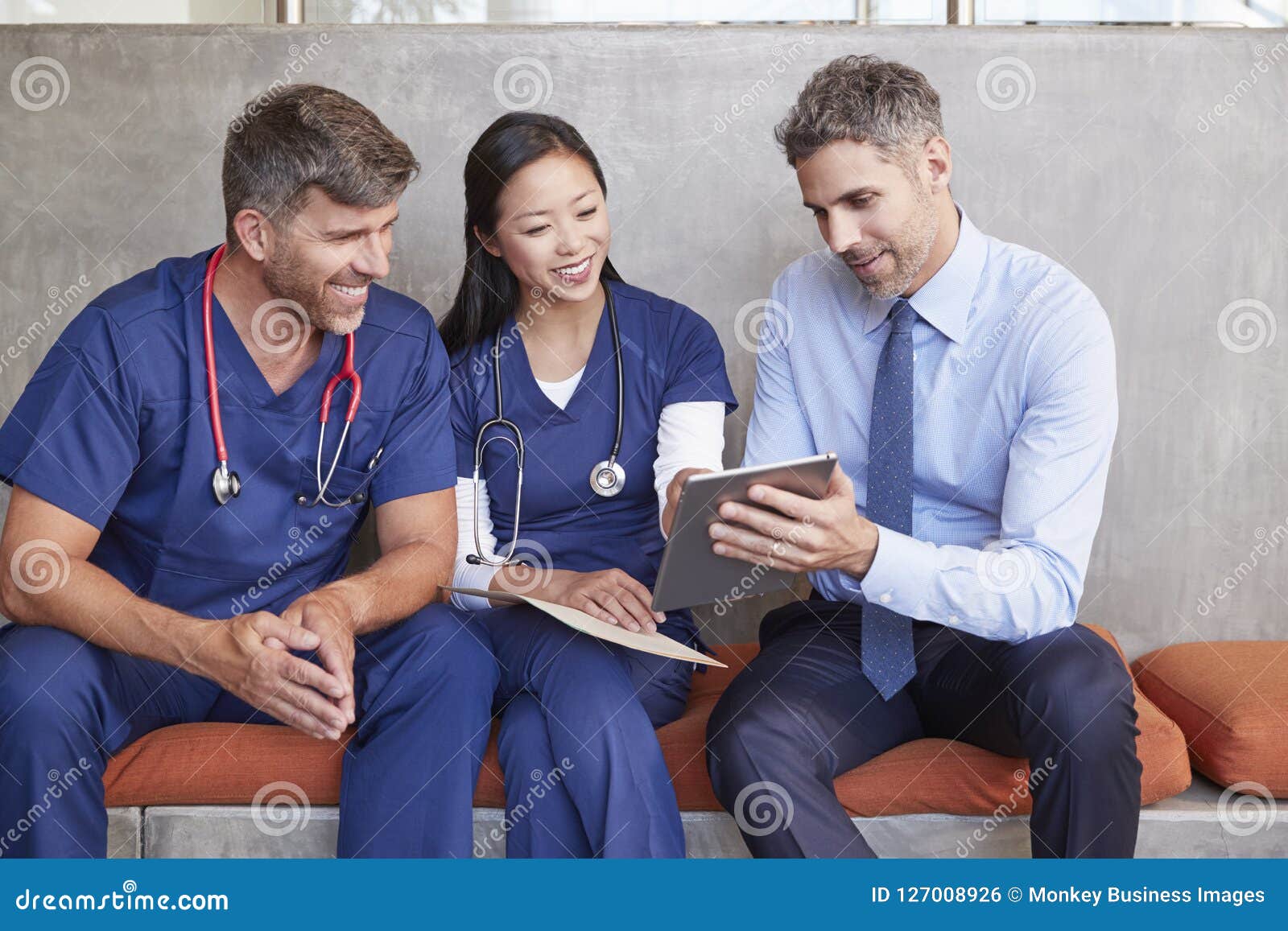 Three Healthcare Workers Sit Using Tablet Computer Together Stock Photo ...