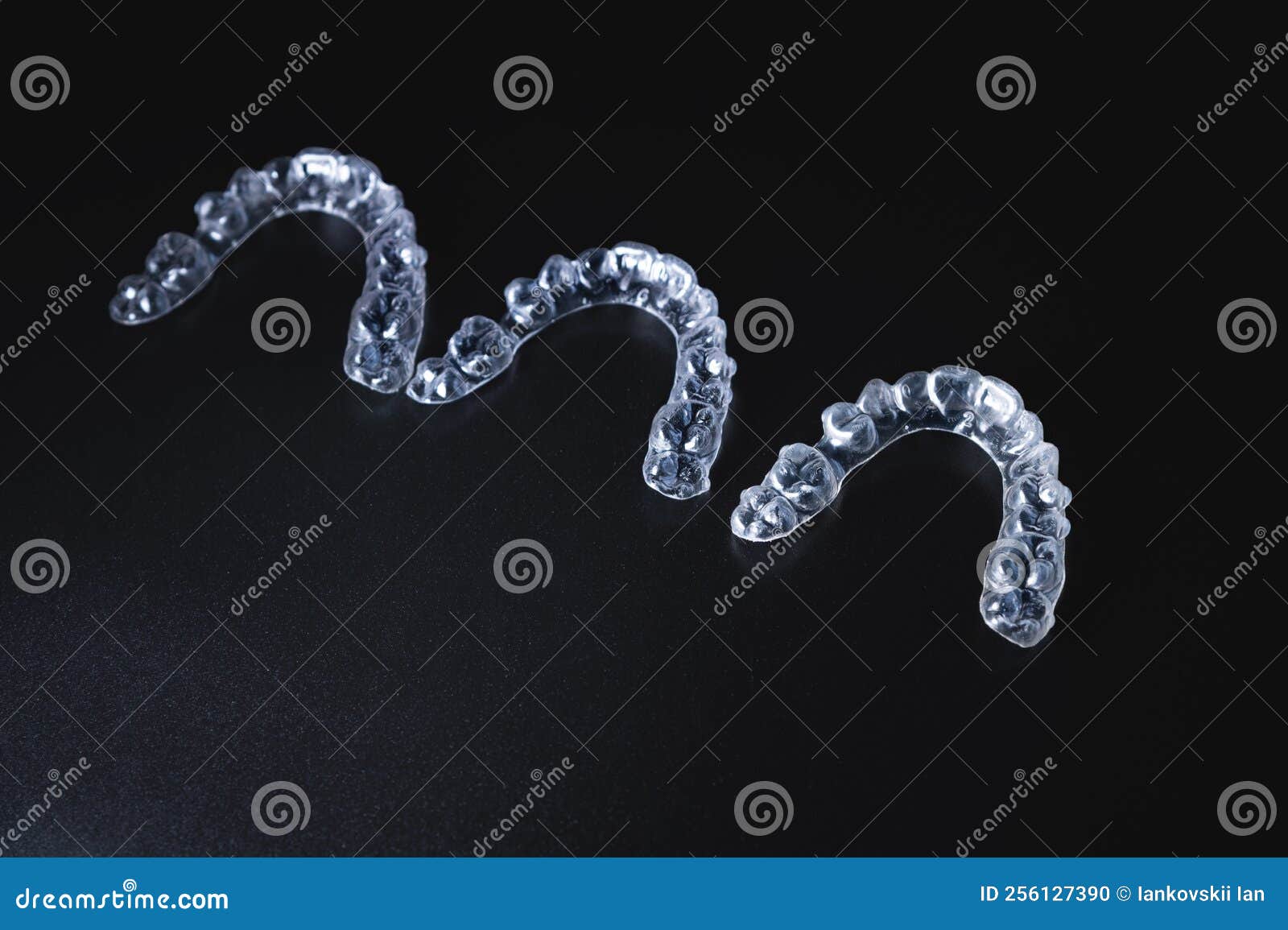 Three Invisible Plastic Aligners Lie Next To Each Other on a Black ...