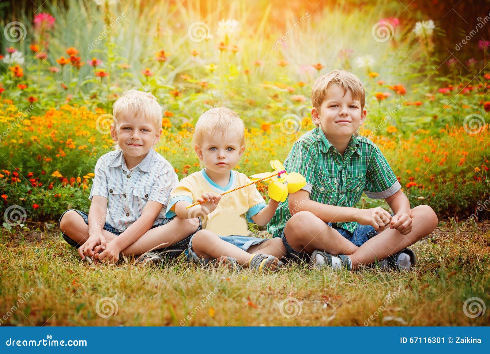 Three Little Brothers Sitting on Grass in Sunny Summer Day. Stock Image ...