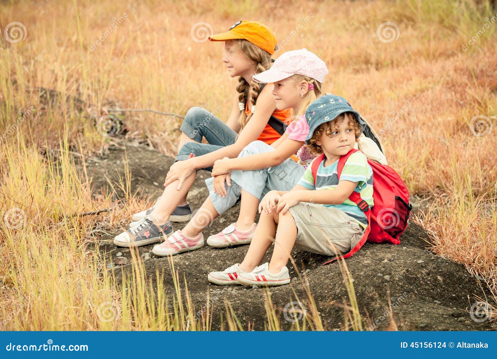 Three Little Kids with Backpack Sitting on the Footpath in the M Stock ...