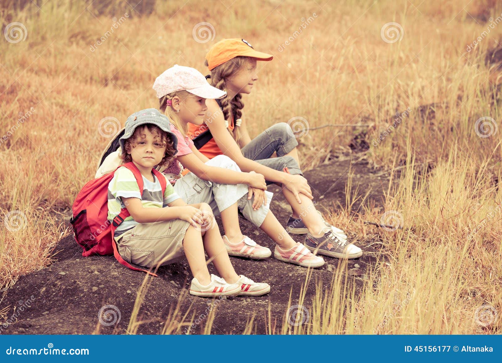 Three Little Kids with Backpack Sitting on the Footpath in the M Stock ...