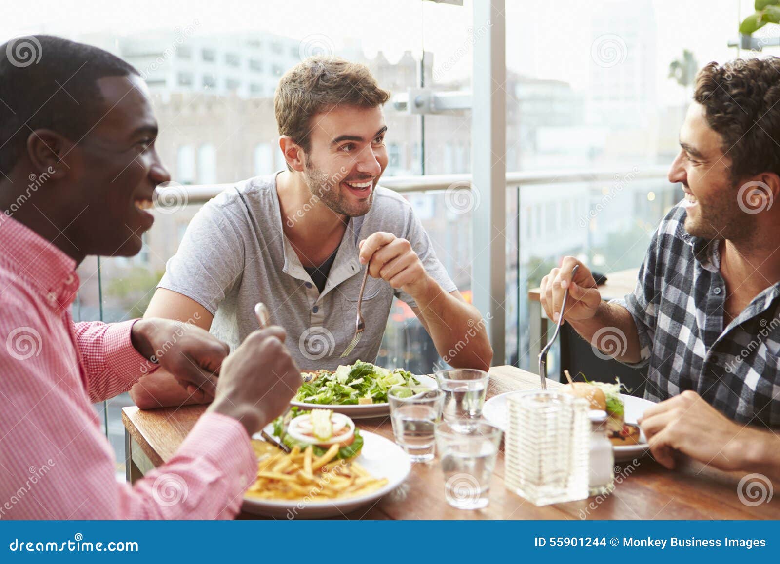 Three Male Friends Enjoying Lunch At Rooftop Restaurant Stock Photo ...