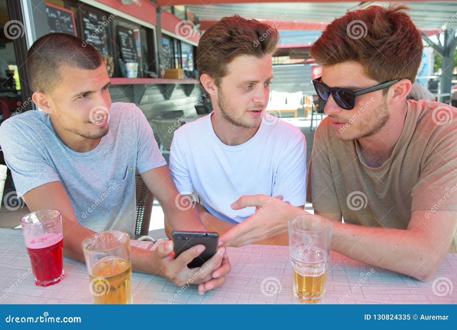 Three Men in Bar Looking at Cellphone Stock Image - Image of beer ...