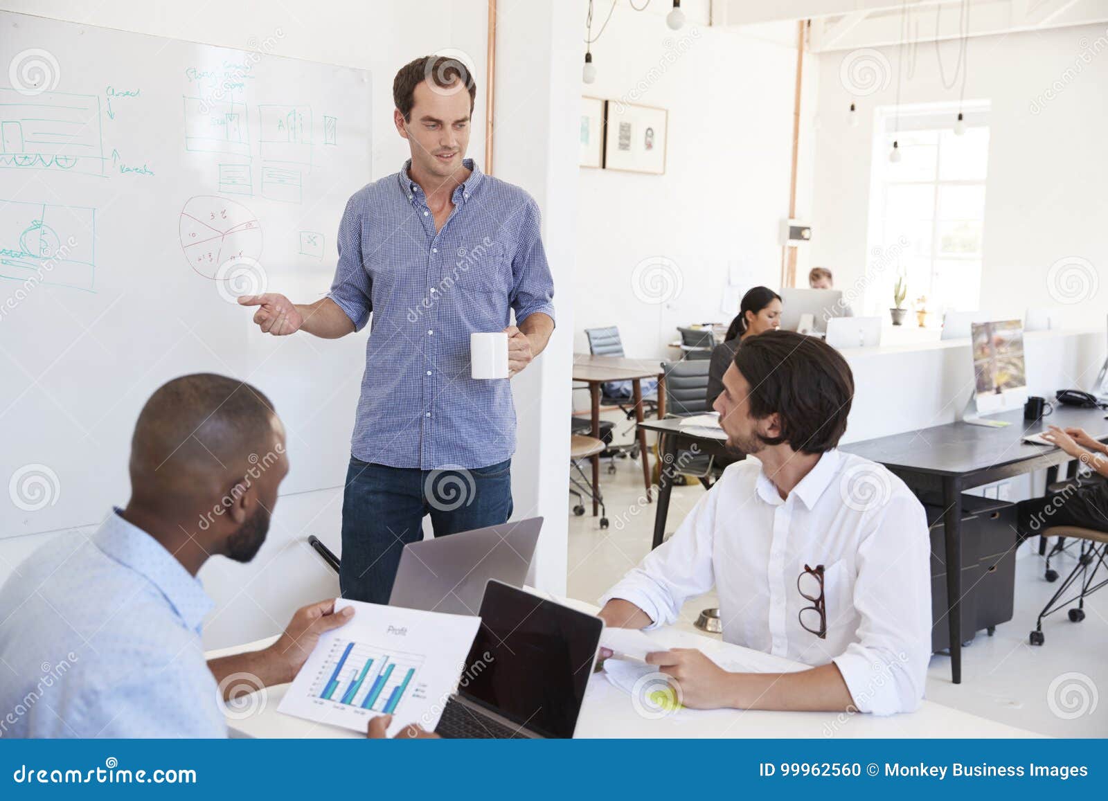 Three Men Discussing Business at Whiteboard in a Busy Office Stock ...