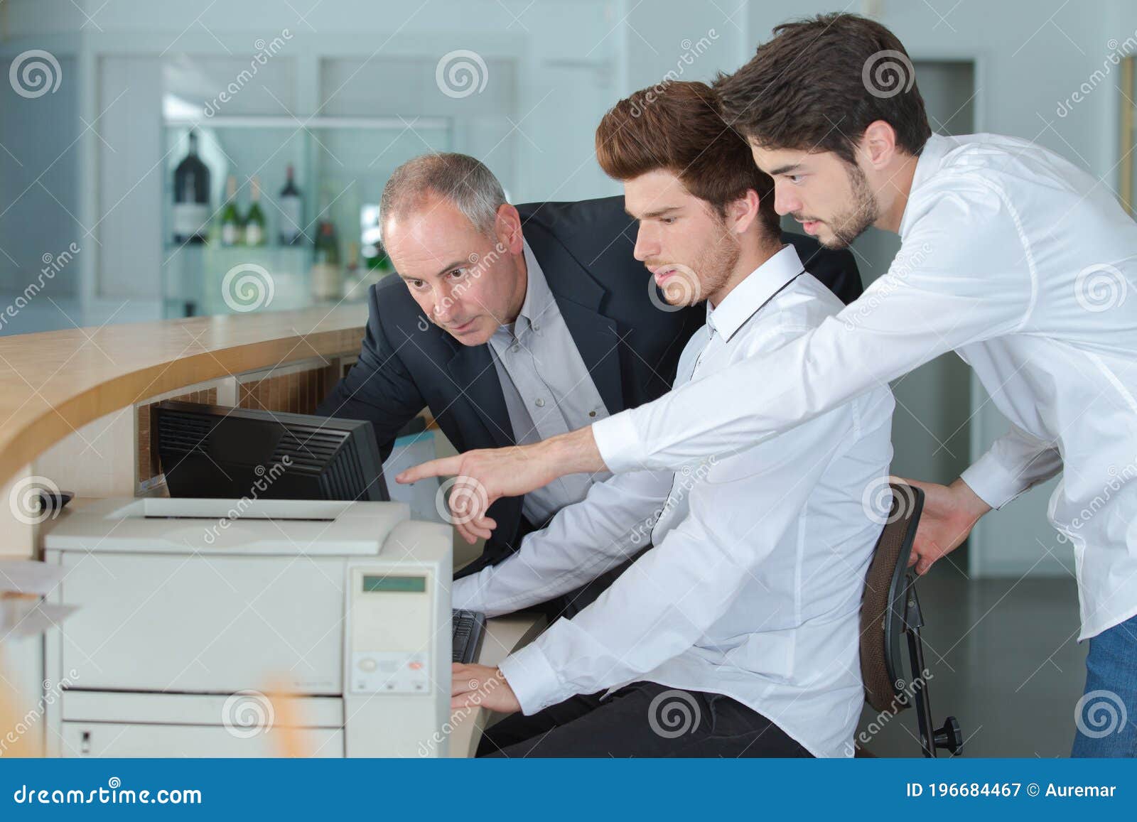 Three Men Looking at Computer Screen Behind Reception Desk Stock Image ...