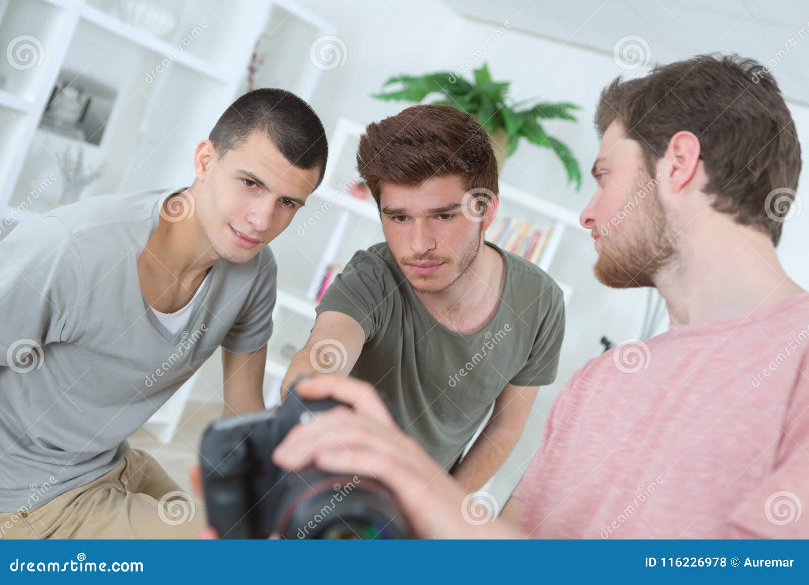 Three Men Looking at Photo on Camera Display Stock Photo - Image of ...