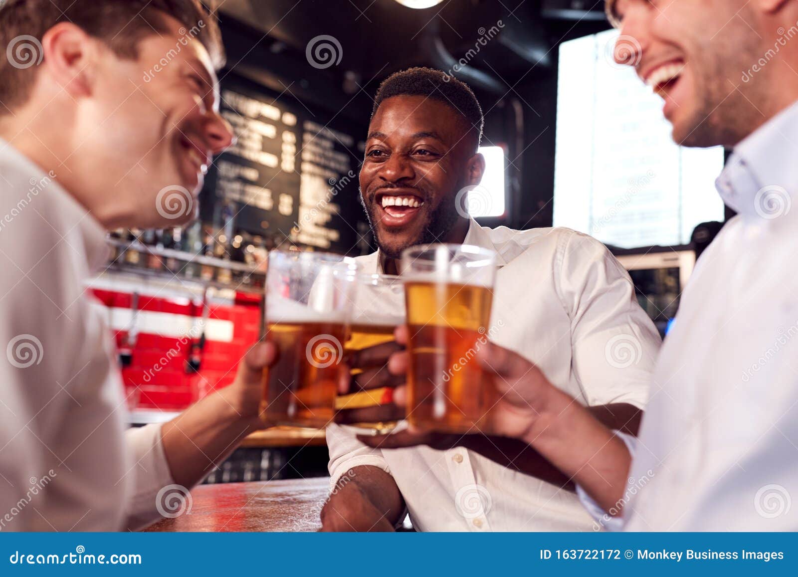 Three Men Making a Toast As they Meet for Drinks and Socialize in Bar ...
