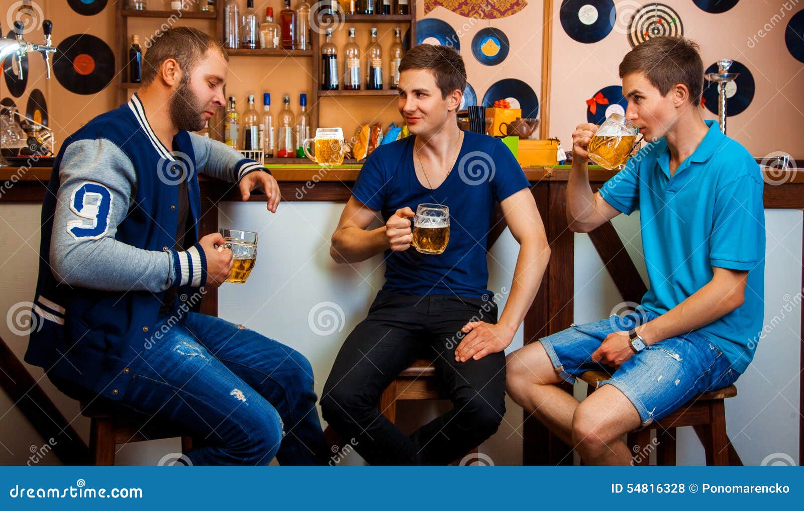 Three Men Talking and Drinking Beer in Bar Stock Photo - Image of ...