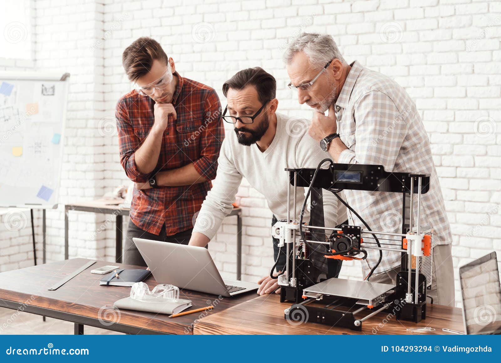 Three Men are Working on Preparing a 3d Printer for Printing. One of ...