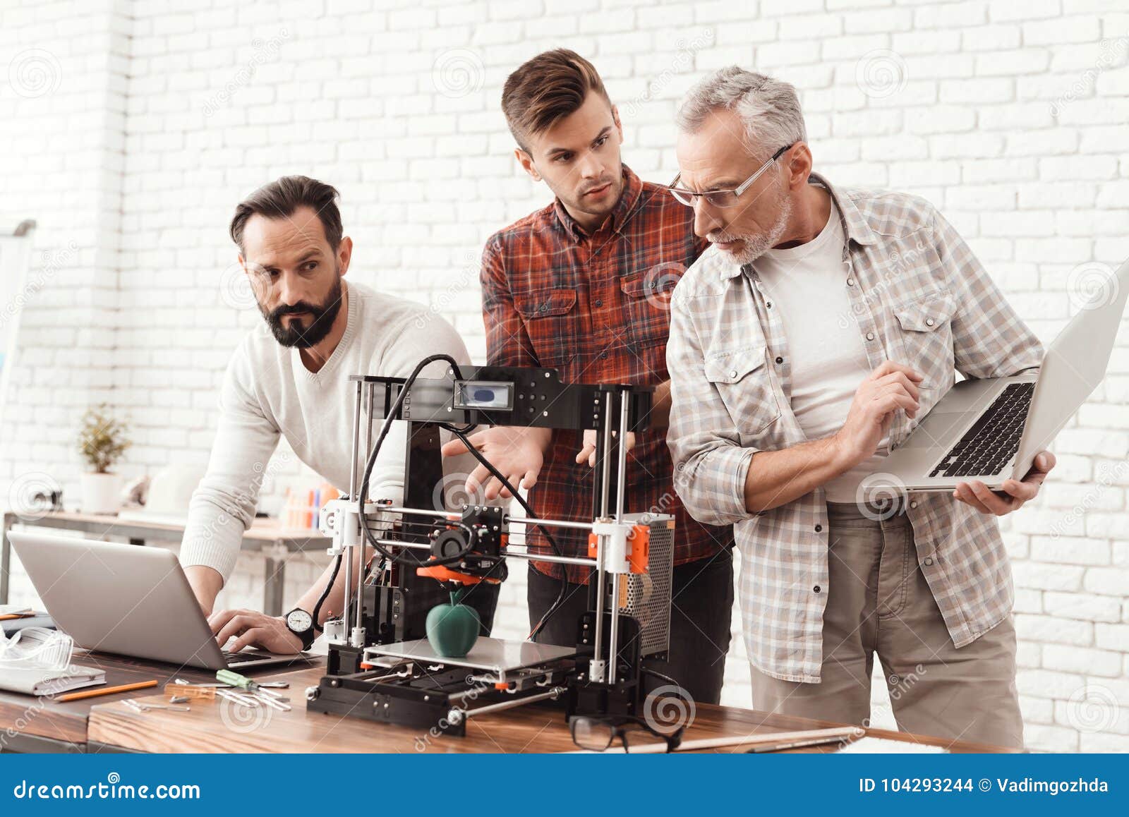 Two Men Set Up a 3d Printer, an Elderly Man Holds a Laptop in His Hands ...