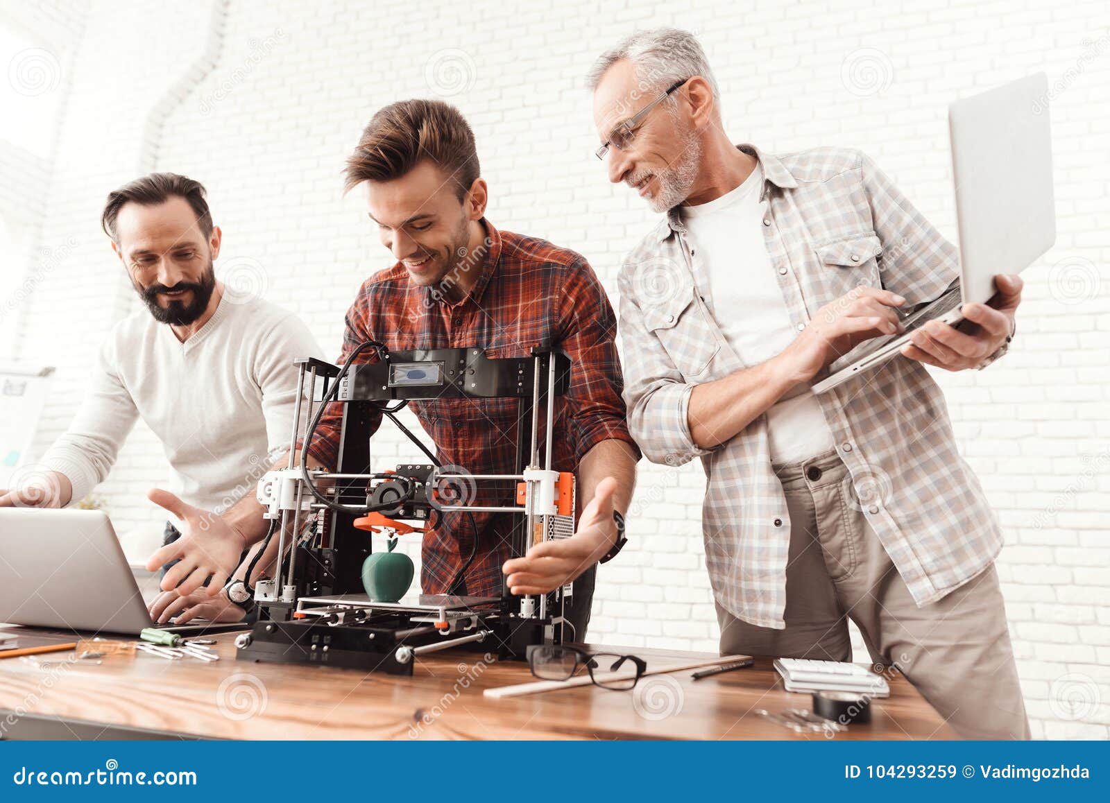 Two Men Set Up a 3d Printer, an Elderly Man Holds a Laptop in His Hands ...