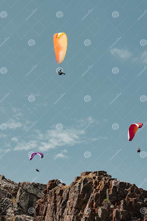 Three Paragliders Forming a Triangle while Gliding Over a Cliff Stock ...