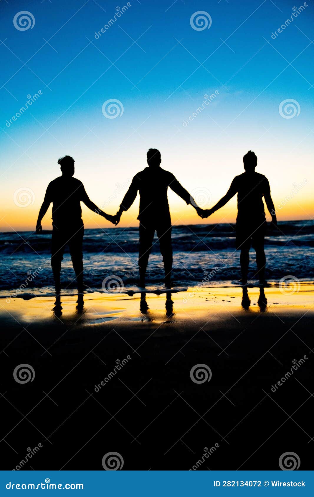 Three People Standing with Hands Linked in a Line at the Beach on a ...