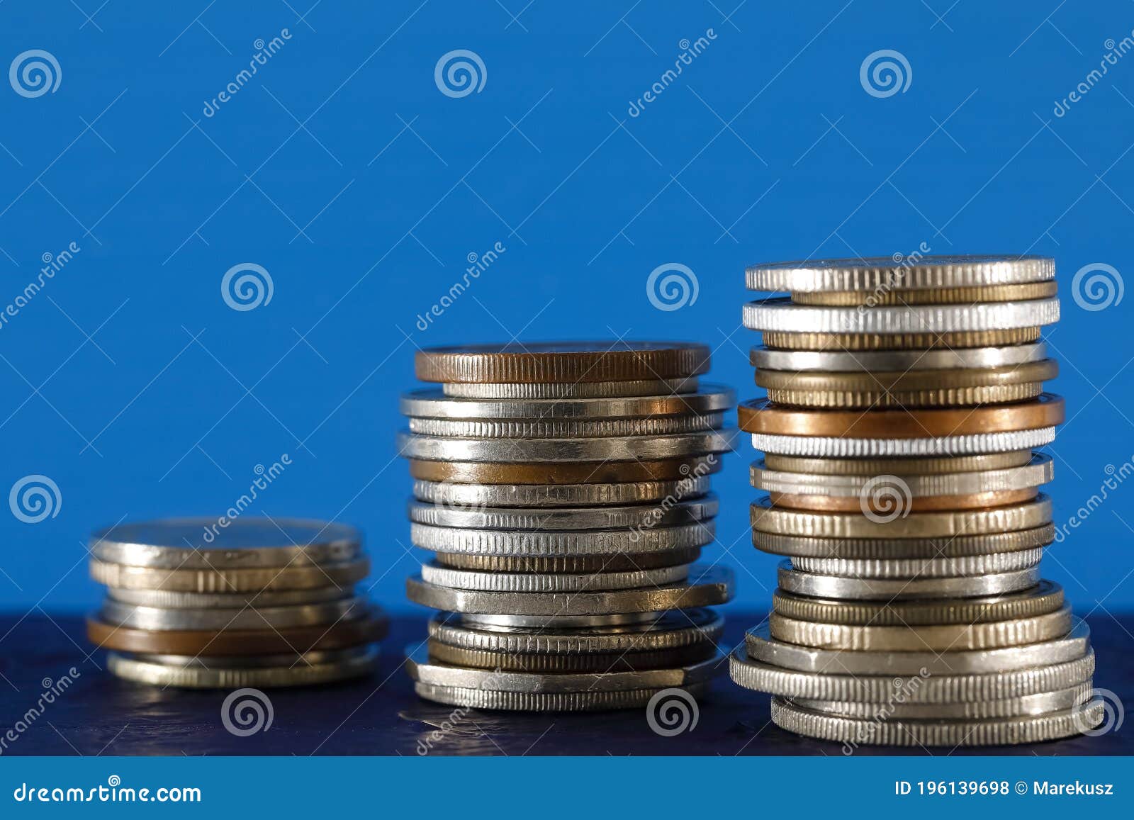 Three Piles of Various Coins Shown on Blue Background Stock Photo ...