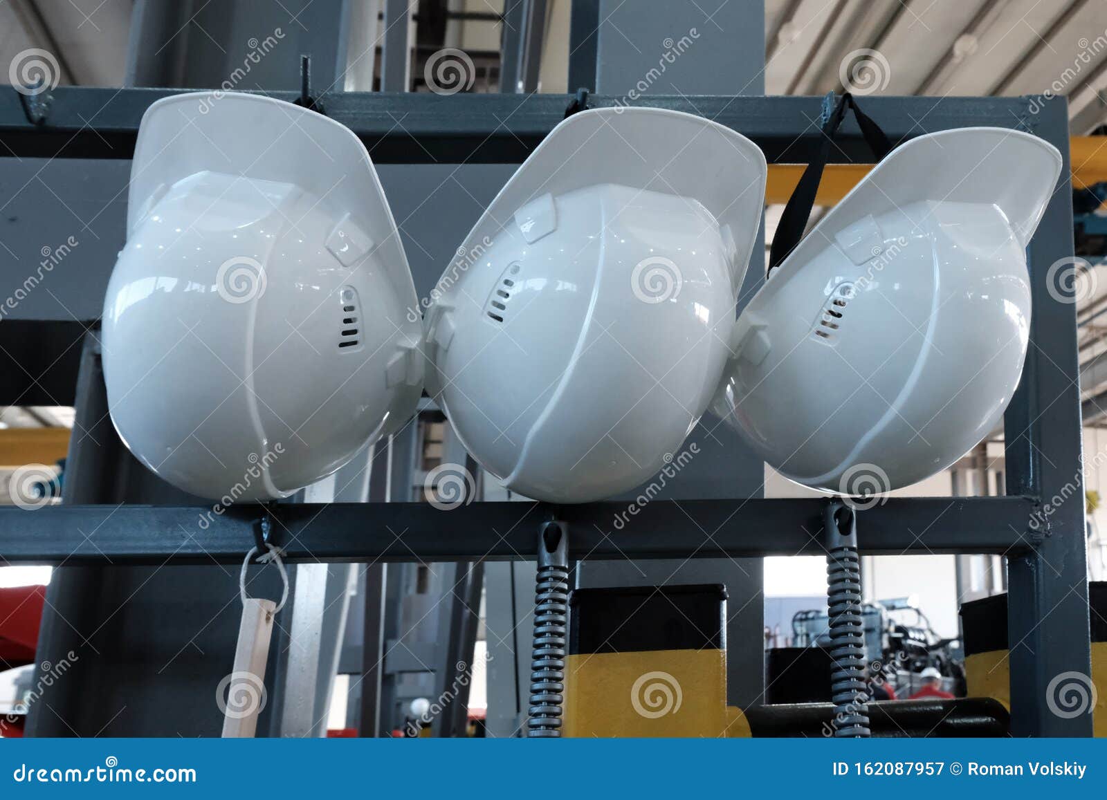Three Protective White Helmets Hang on the Rack in the Factory. the ...