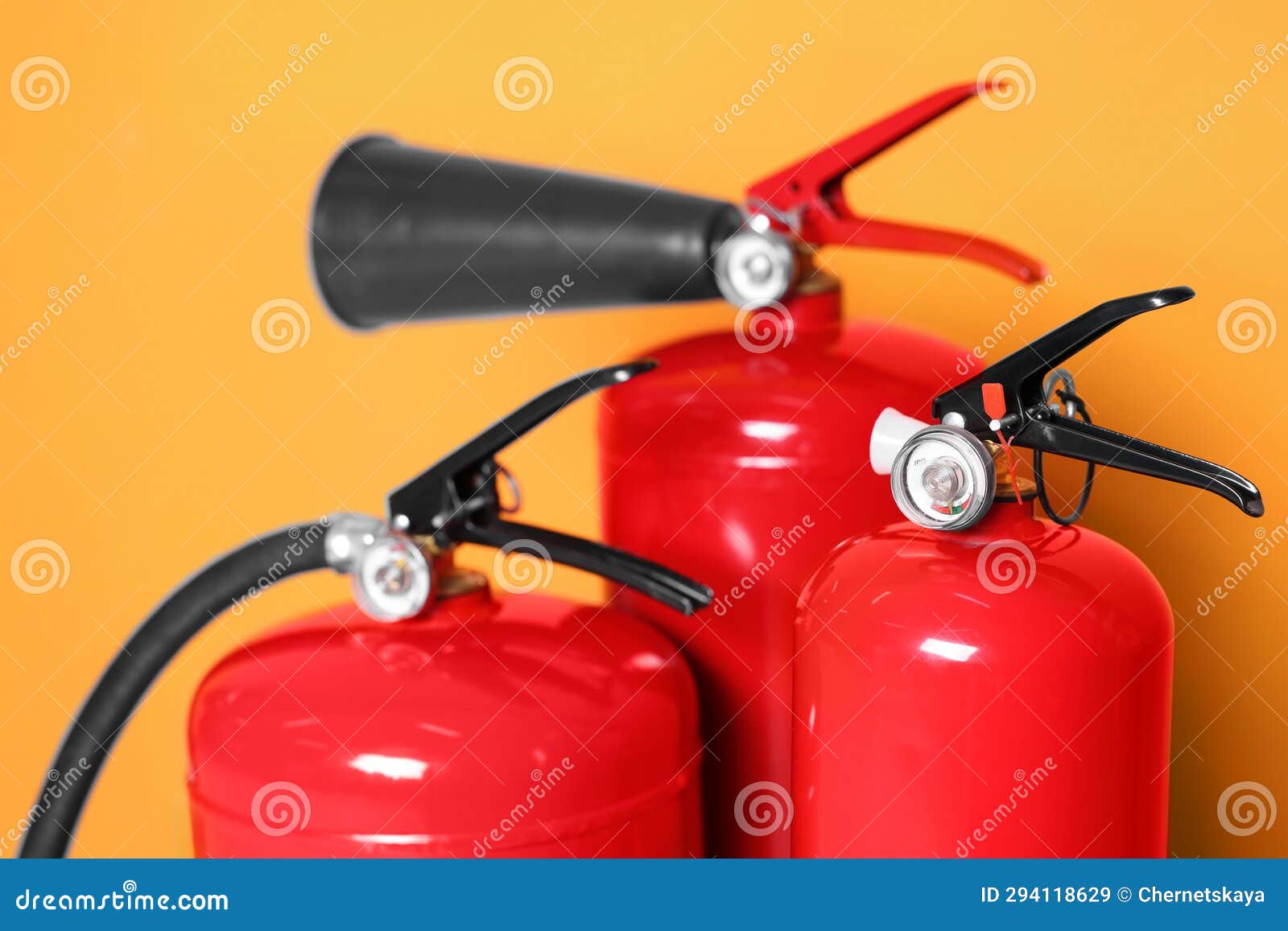 Three Red Fire Extinguishers on Orange Background, Closeup Stock Image ...