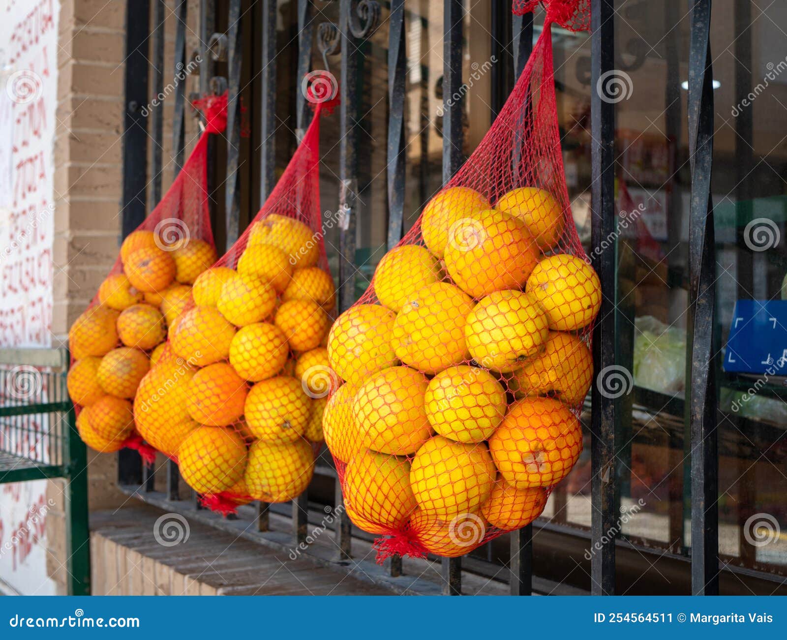 Three Packaging Nets with Oranges Hanging on a Window Steel Bars for ...