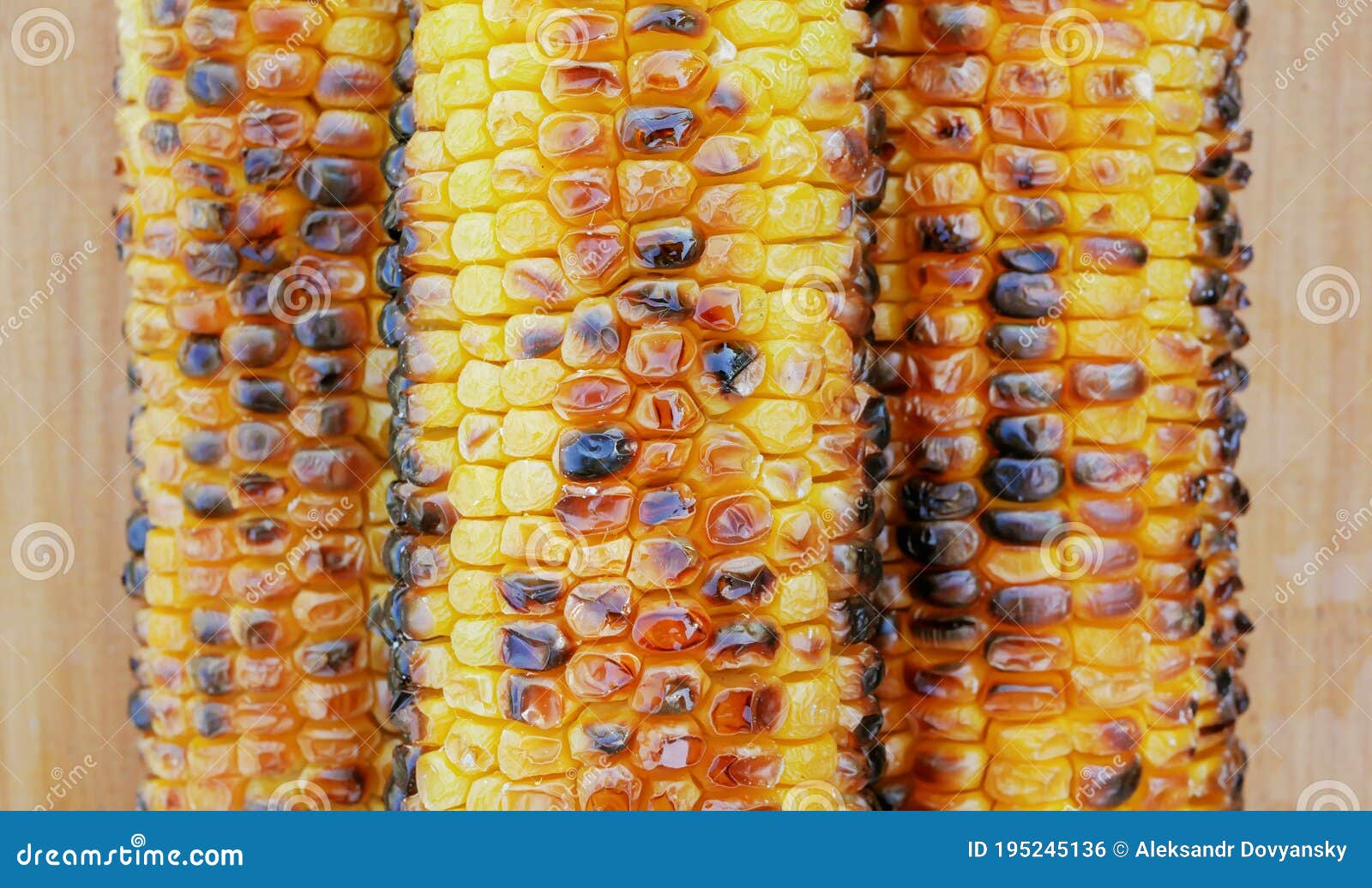 Three Ripe Fried Corn Lie Side by Side on a Wooden Background. View ...
