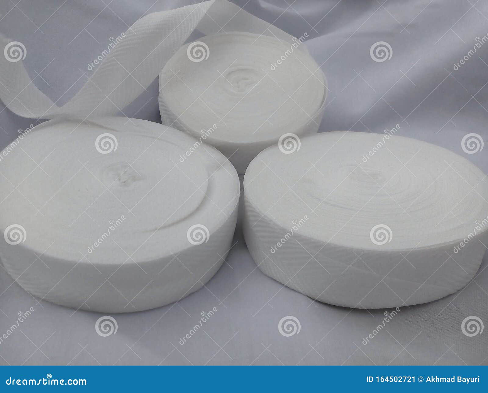 Three Rolls of White Ribbons on a Textured White Cloth Stock Image ...