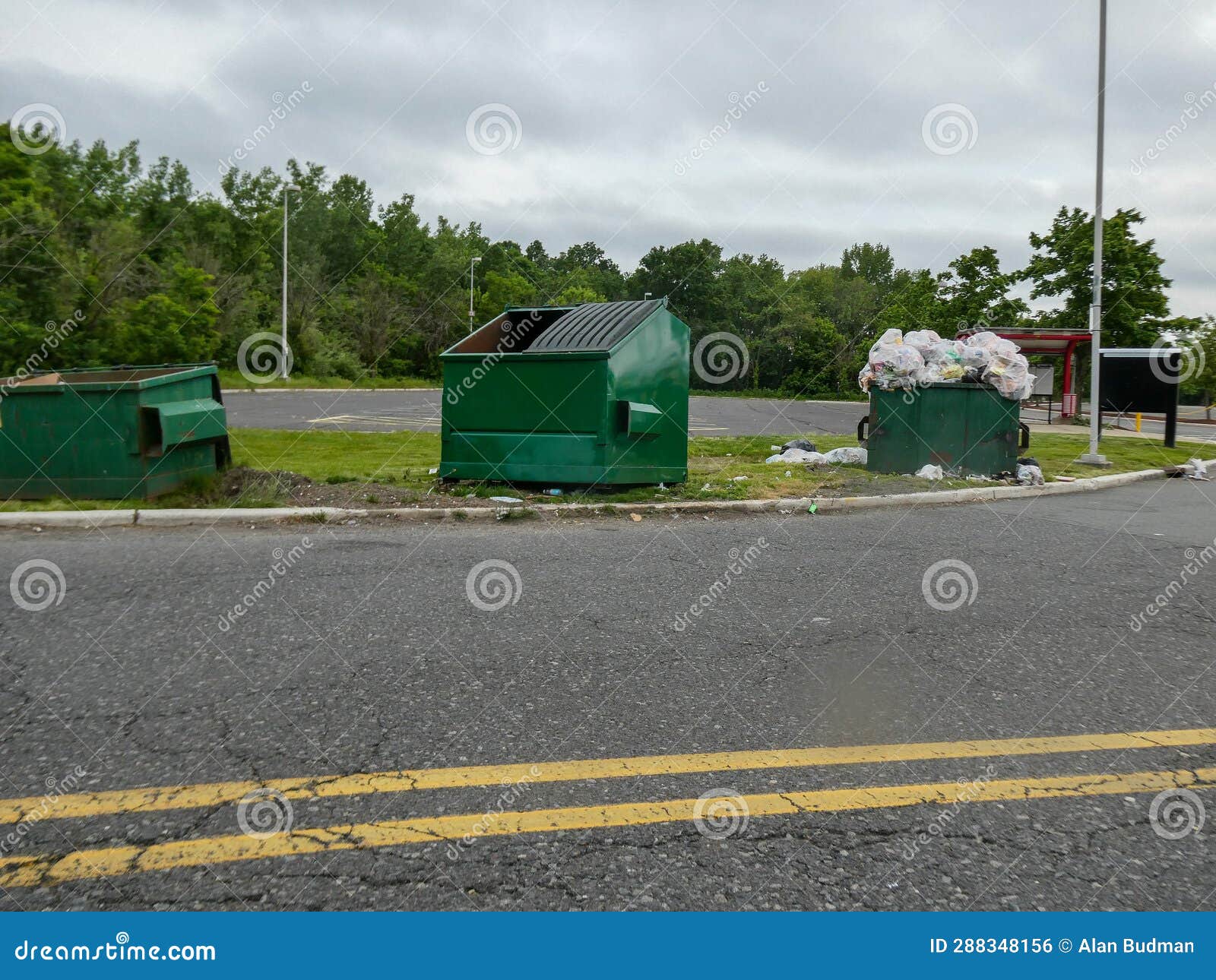 Three Small Dumpsters Near a Road. Two are Empty but the Third is ...