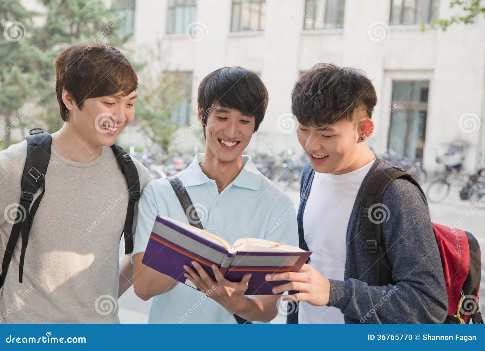 Three Students Discussing and Looking at the Book Stock Photo - Image ...