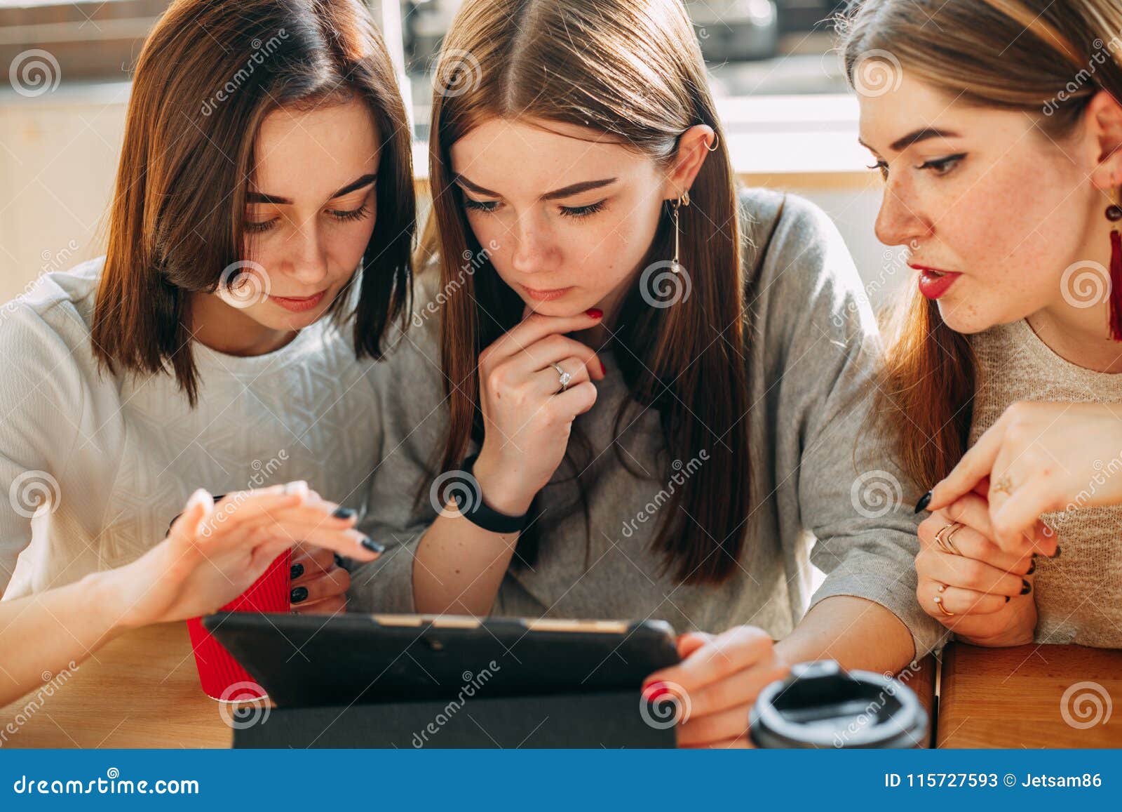 Three Students Reading Article Using Tablet Pc at Coffee Break. Stock ...