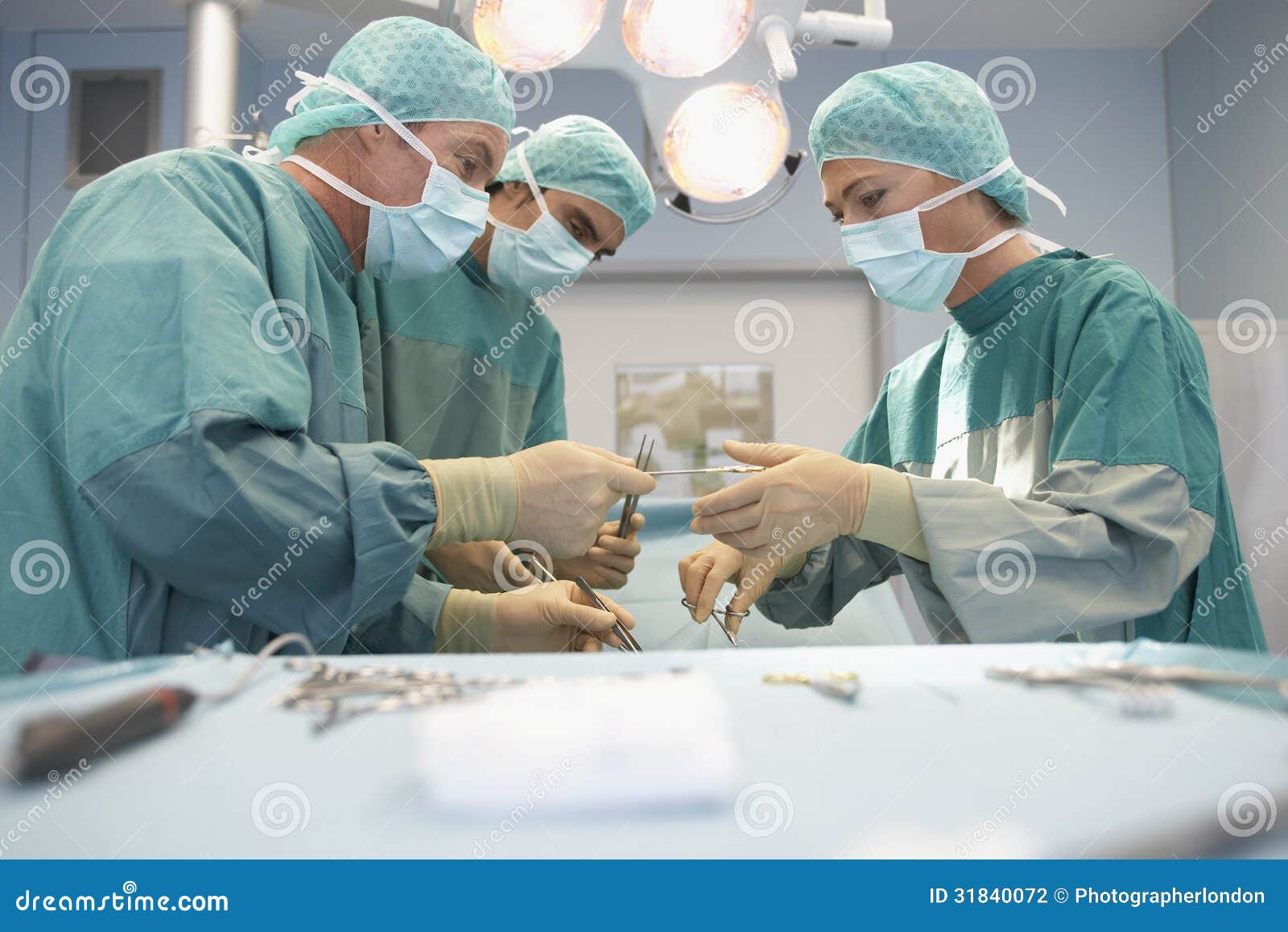 Three Surgeons At Work Operating In Surgical Theater Saving Patient And ...