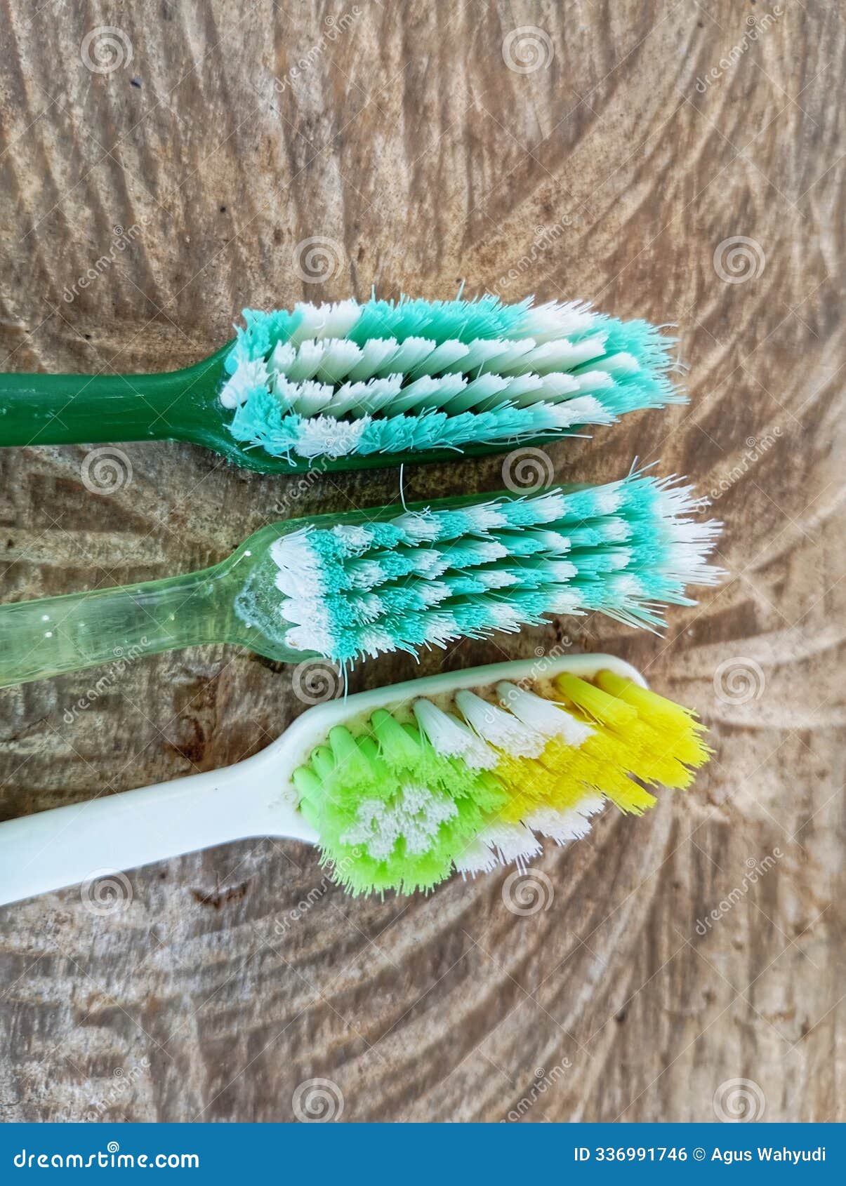 Three Toothbrushes with Different Colored Bristles Lying on a Wooden ...