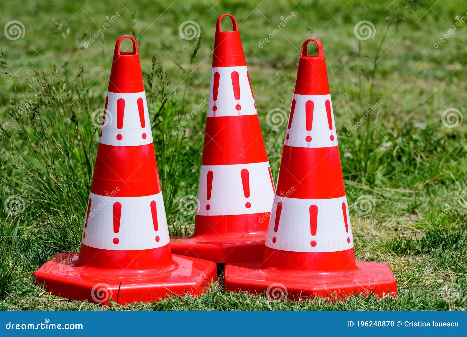 Three Traffic Reflective Safety Cones on Red and White on Green Grass ...
