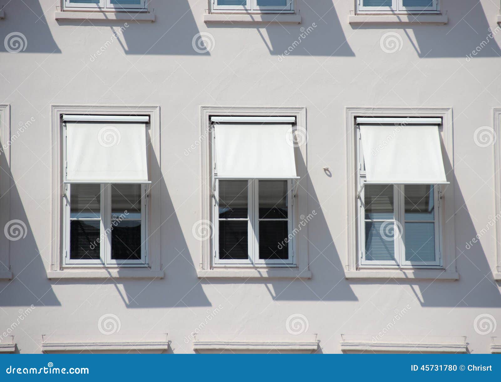 Three Windows on Grey Building with White Awnings and Shadow Stock ...