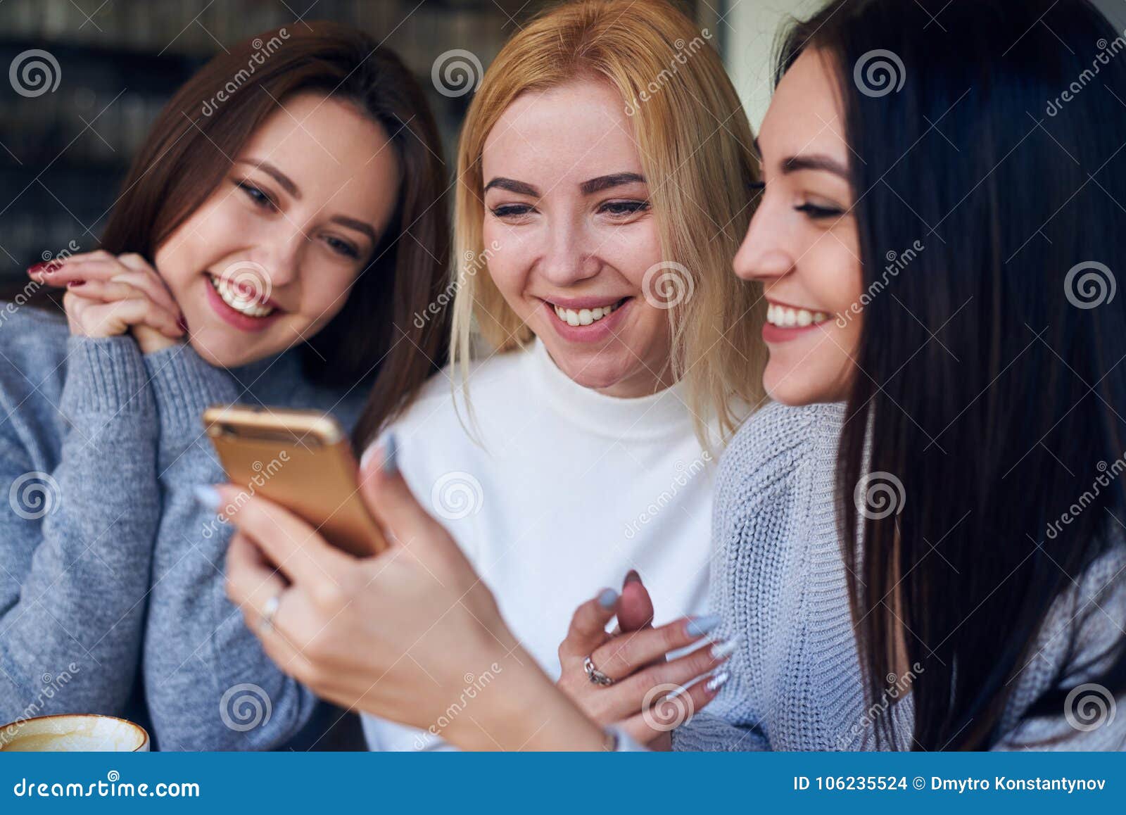 Three Young Beautiful Women Using Mobile Phone at Cafe Stock Photo ...